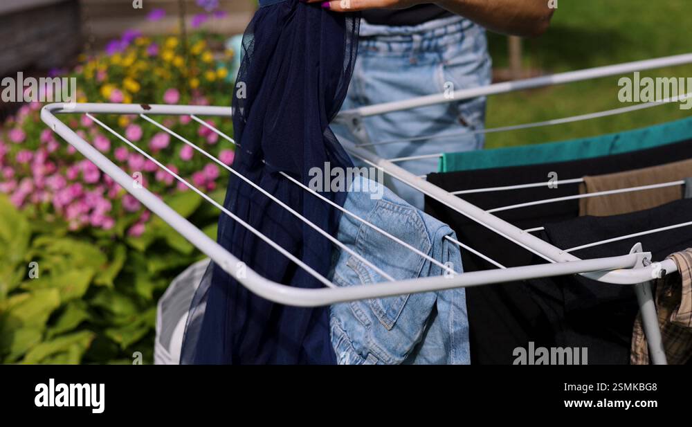 woman hang out the laundry outdoors on clothes airer rack at home ...