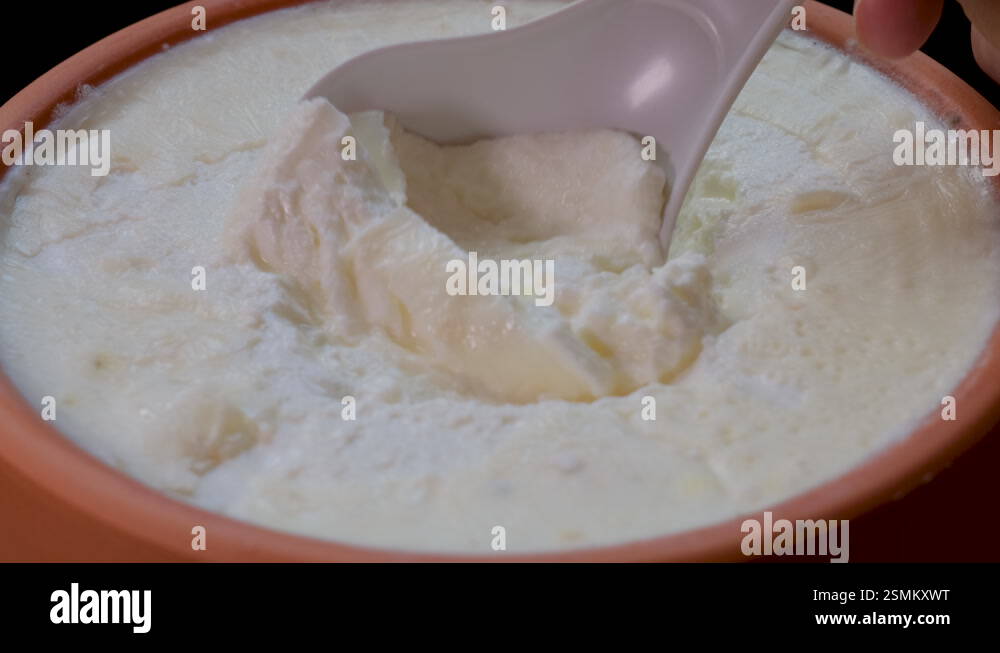 Close-up video showing a spoon scooping yogurt from a clay pot Stock ...