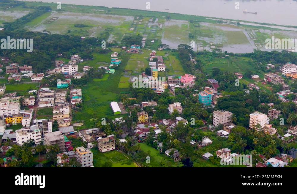Urbanization along the Kirtankhola River with cargo ships in view at ...