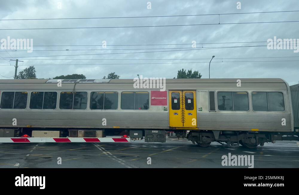 Queensland Rail (QR) trains pass railway traffic light and barrier ...