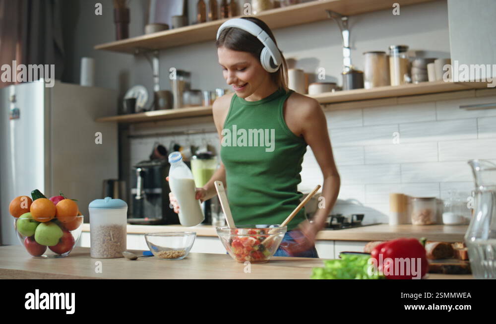 Cooking woman listen music in wireless headphones closeup. Girl pouring ...