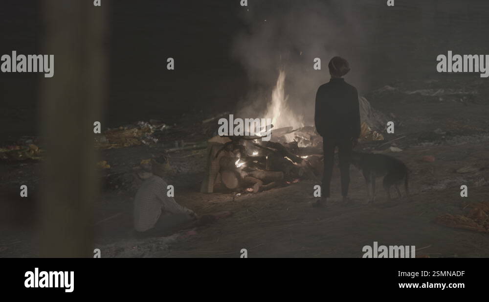 Varanasi, Uttar Pradesh, India. Indian worker man watching fire during ...