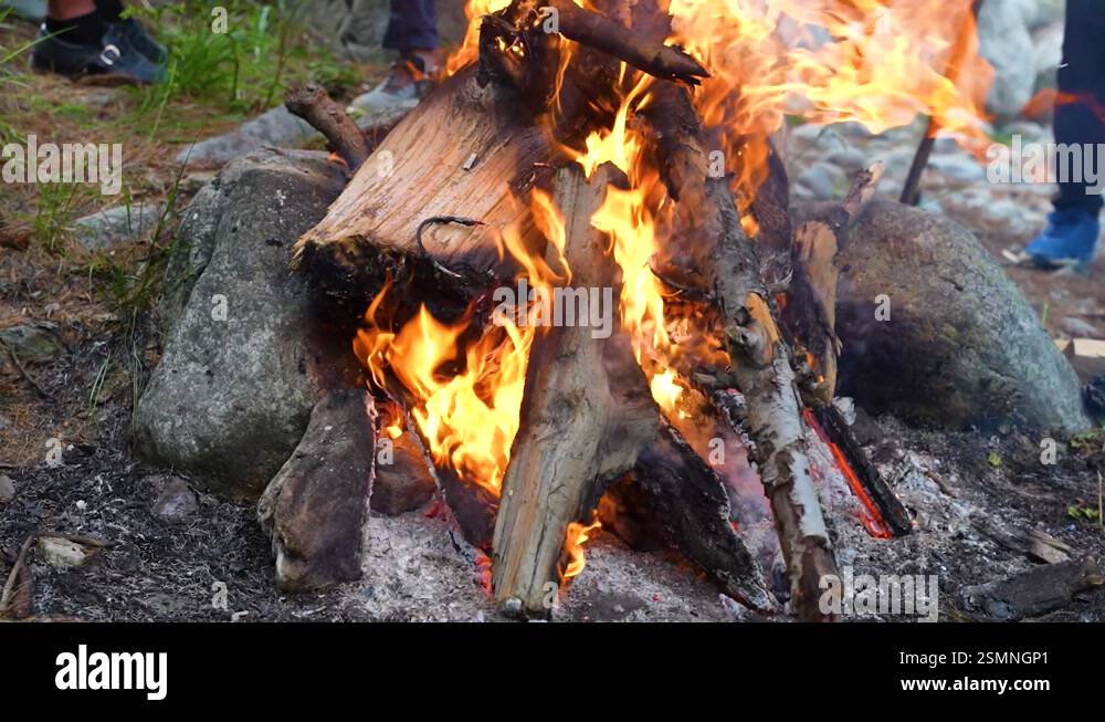 Large campfire burning intensely with wooden logs and stones in an ...