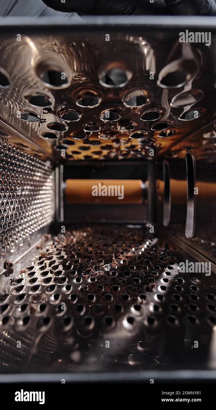 Grating a chocolate bar into a grater to make shavings for making ...