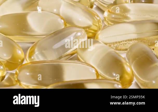 Yellow capsules medical pills rotating closeup. Vitamin C, Omega 3 in ...