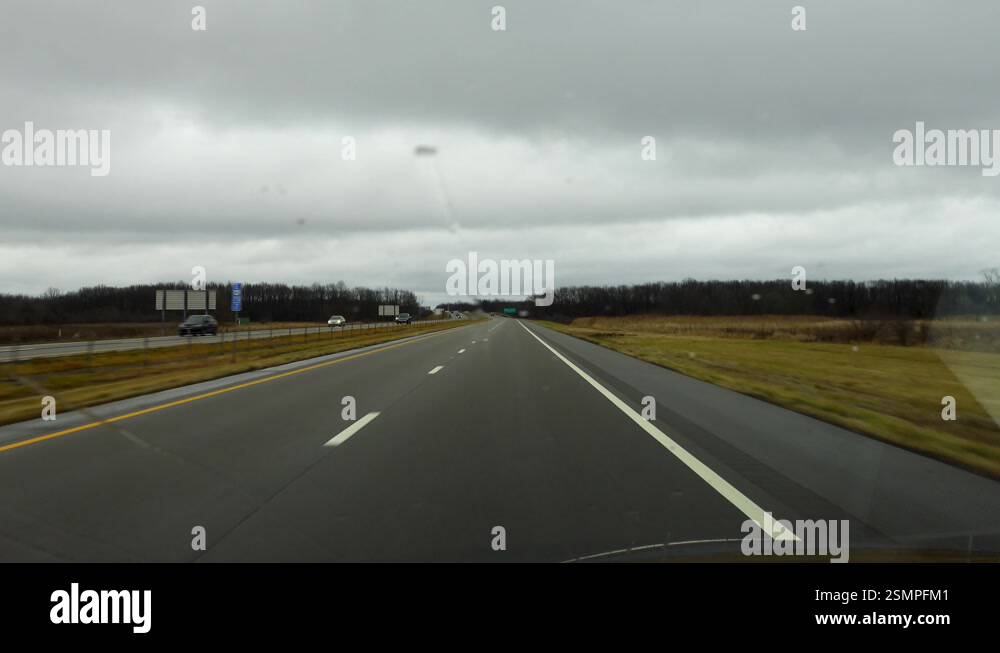 A drive down an open highway on a cloudy, overcast day. The empty road ...