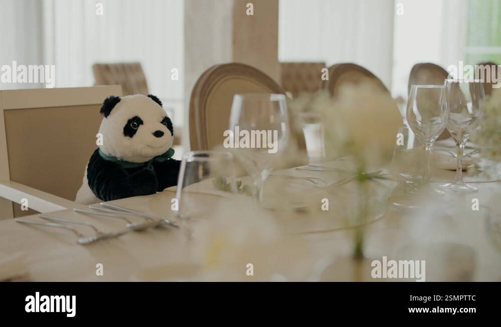 Table setting with a stuffed panda toy placed on a chair, adding a ...