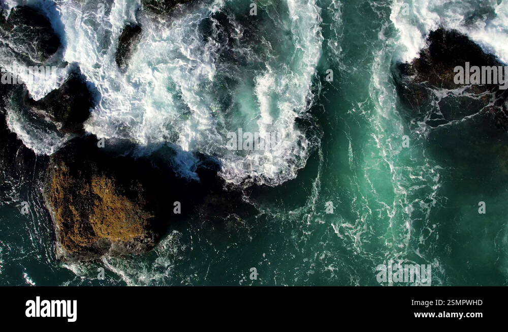 Drone rotating 360 degrees over the ocean water as a wave crashes into ...