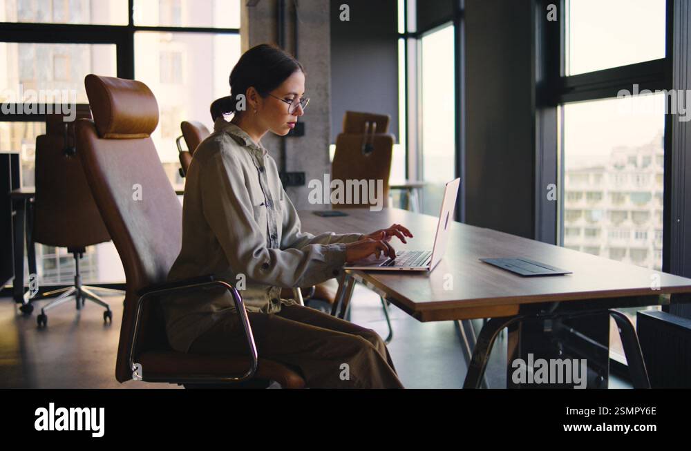 A professional woman is working diligently at a modern office desk ...