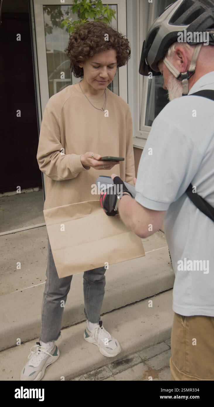 Female Customer Paying with Phone and Taking Paper Bag from Delivery ...