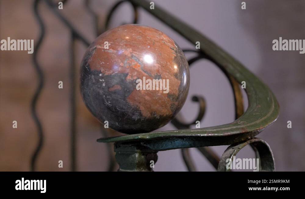 Close-up shot of a marble ball stuck on top of a handrail within a ...
