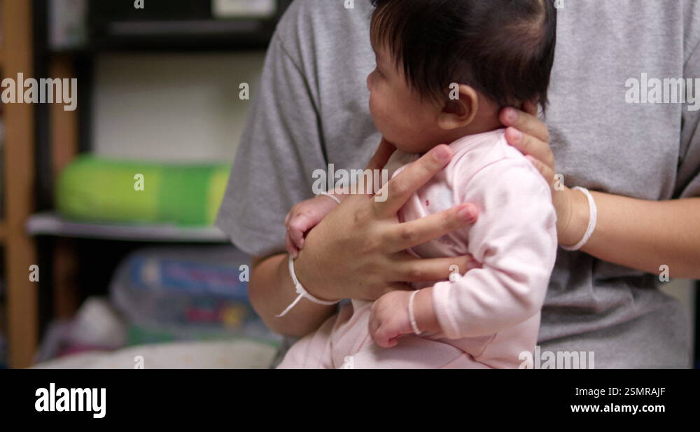 Holding up a newborn child's neck as the mother is tapping the baby's ...