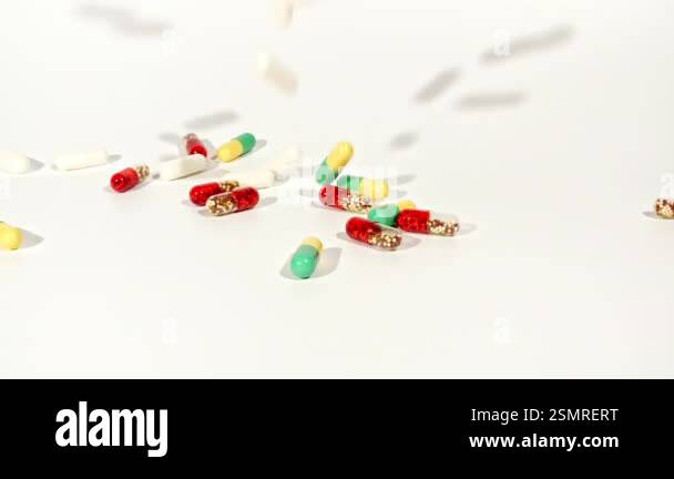Closeup of different medical Pills falling on table on white background ...