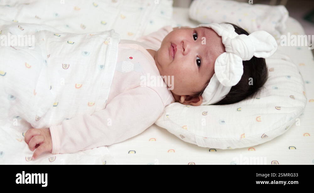 Stretching her arms while looking from side to side, a cute newborn ...