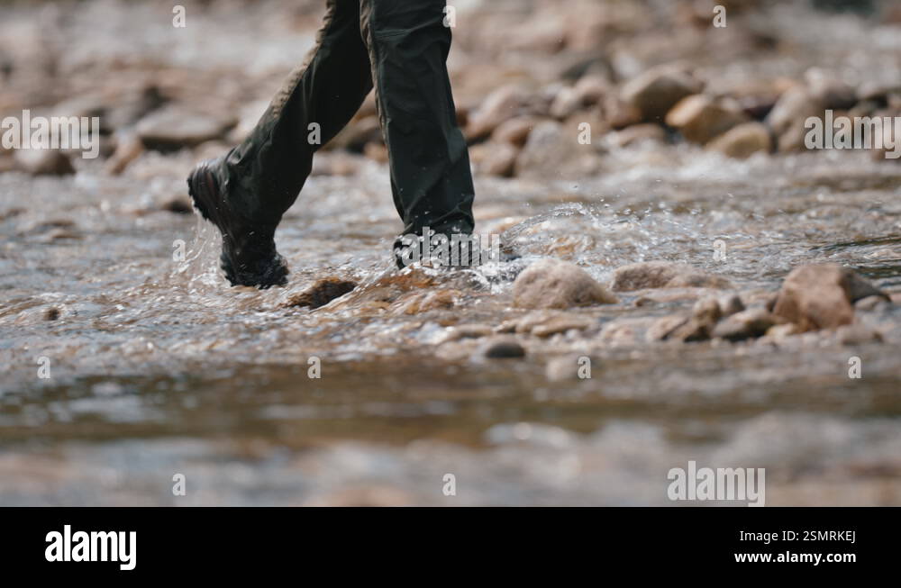 Male hiker in trekking shoes walk crossing river steps on stones in ...