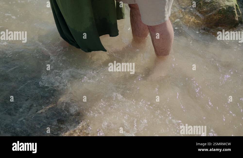 Feet of a couple standing together in shallow water, with the woman in ...