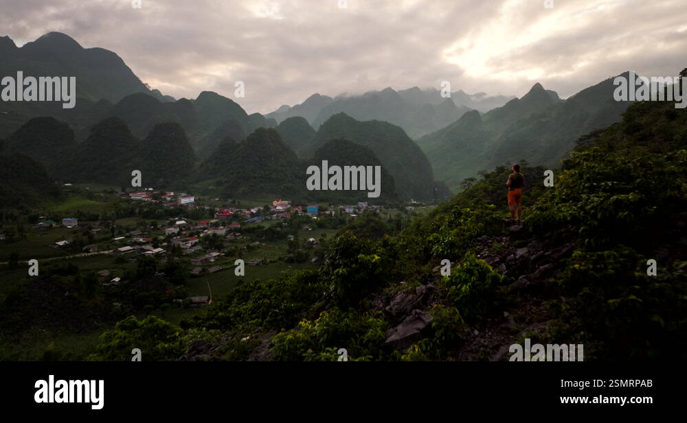 Male traveller on mountainside looks down on scenic Lung Ho village on ...