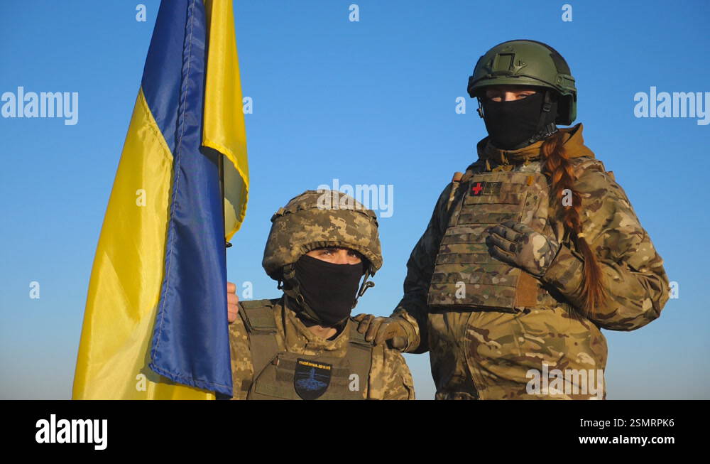 Military couple of ukrainian army with flag of Ukraine posing on camera ...