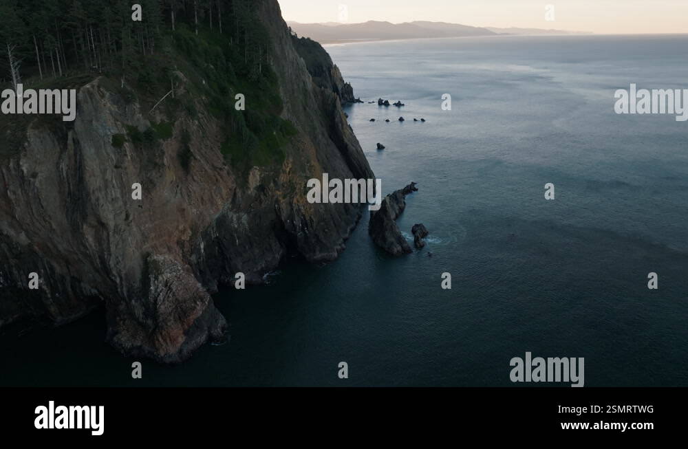 Drone pushes forward past dry dirt cliff as grass drops off into ocean ...