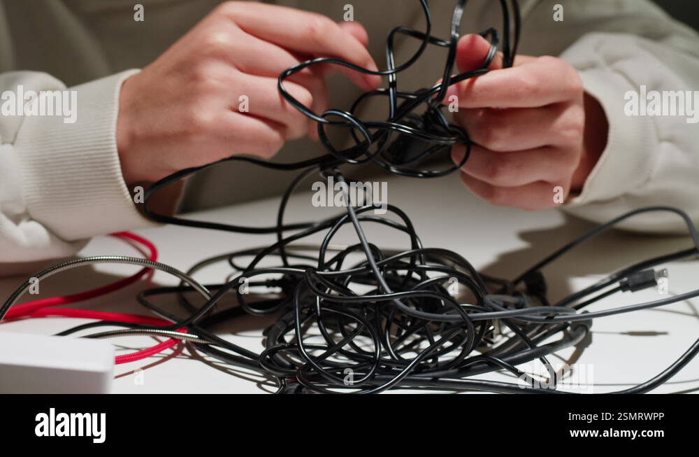 Young woman trying to untangle many various of wires close-up. Tangled ...