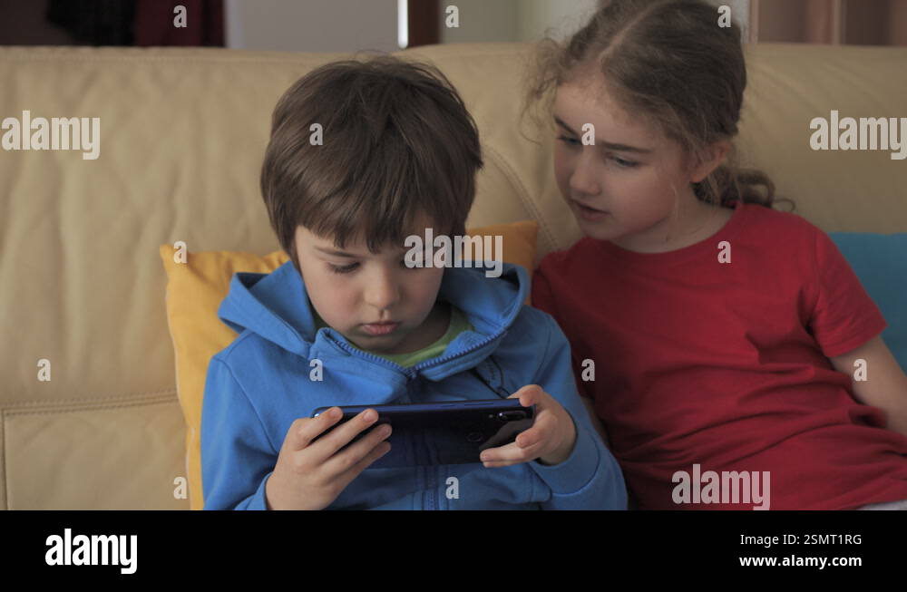 Children Playing Games In Phone at Home on Couch. Kids Playing Video ...