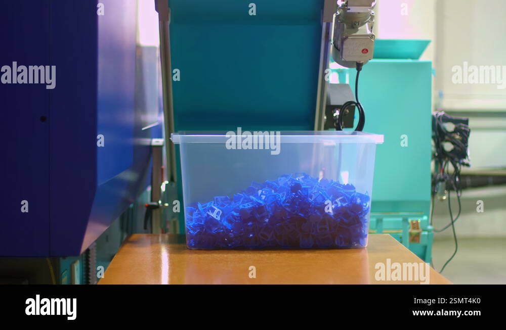 A container filled with blue plastic parts in an automated ...