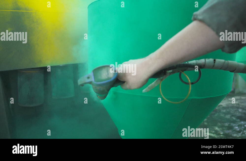 Worker spraying green paint on detail in painting chamber. Painter ...