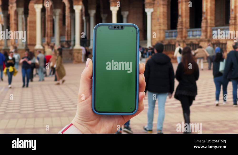 Close up of phone with vertical green screen in hands on city buildings ...