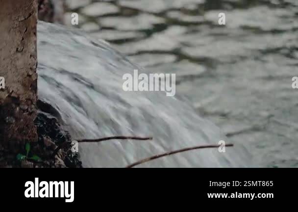 Water flows from a concrete pipe into a river. This clear water stream ...