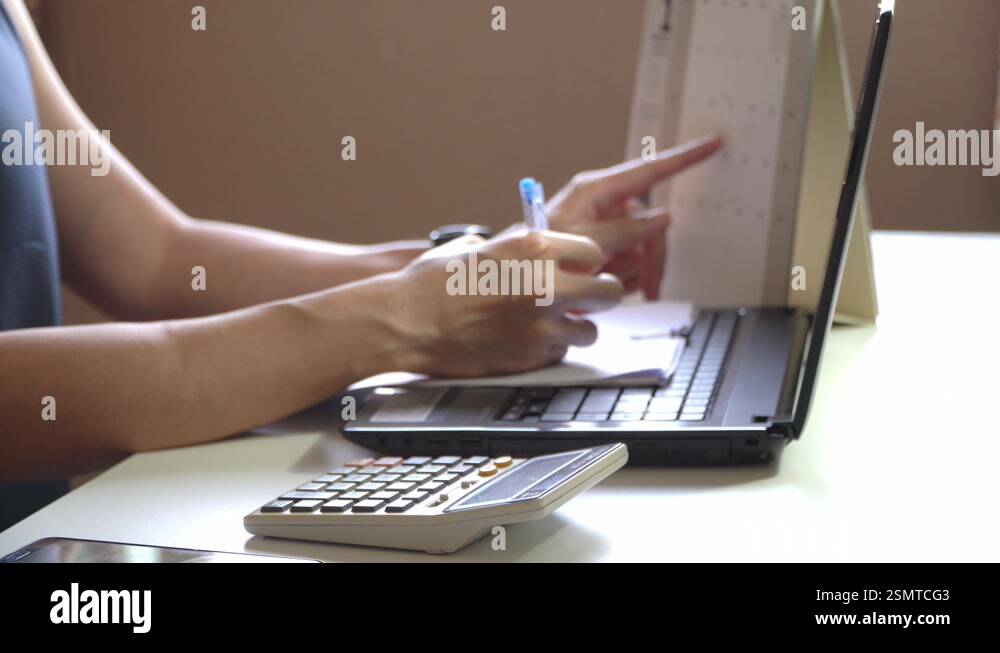 Side view of male hand using a calculator to calculate the first ...