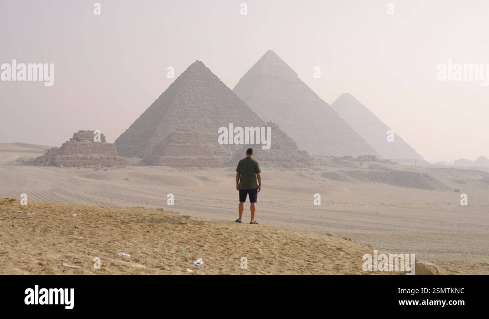 Man Standing Near Giza Plateau Pyramid Complex At Sunrise In Egypt ...