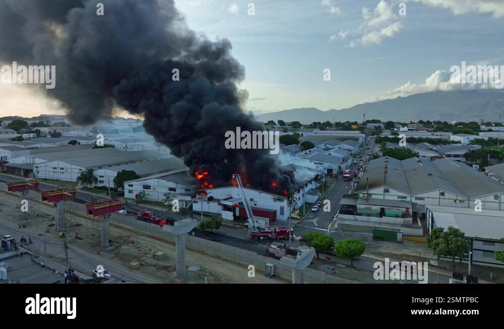 Thick black smoke rising from a major warehouse fire. Tilt up ascending ...