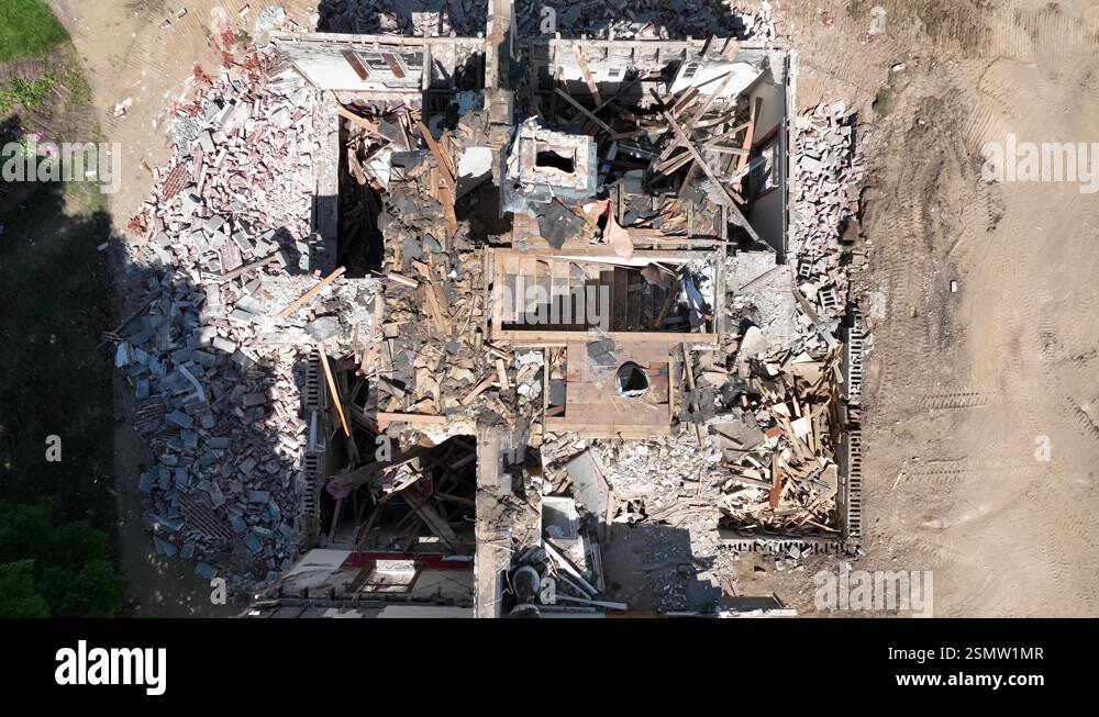Collapsed building structure with debris scattered in a dirt lot ...