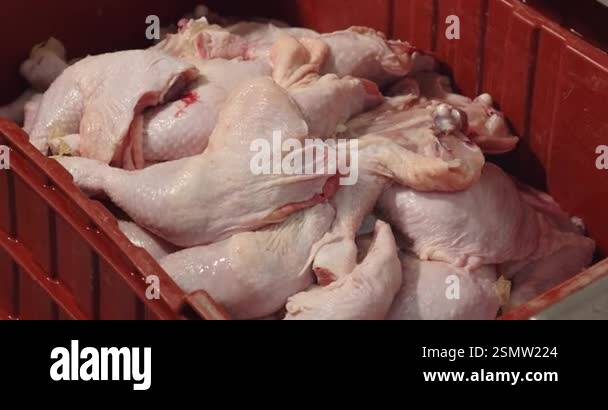 A pile of raw chicken legs stacked inside a red plastic container ready ...