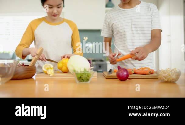 Preparing vegetables, Asian brother and sister chopping ingredients ...