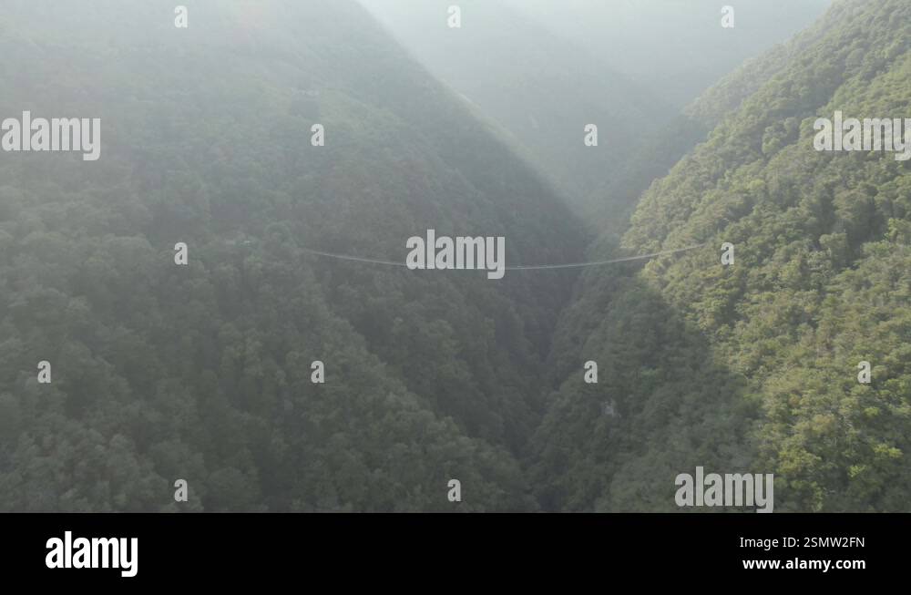 Flying towards mountain suspension bridge with lens flare in camera ...