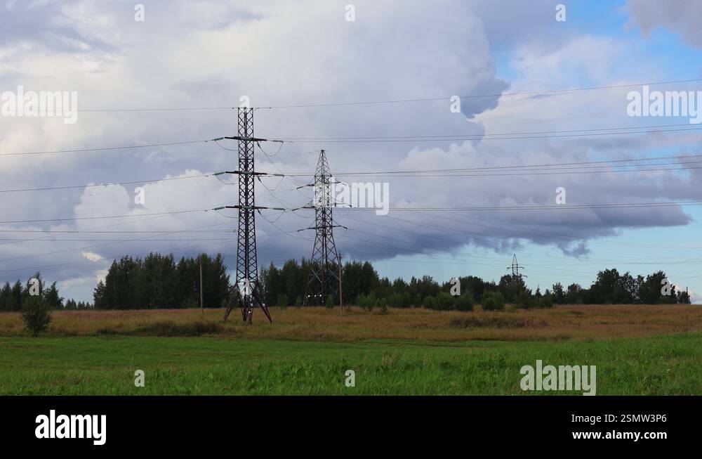 High voltage power line pylons in the field and blue sky with clouds ...