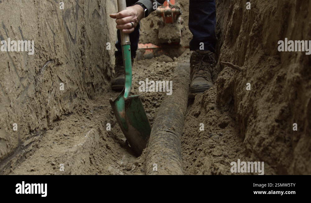 Construction worker clearing out old weeping tile - foundation repairs ...