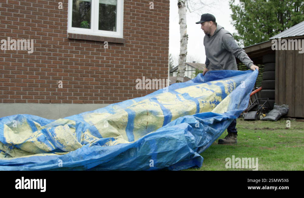 Construction worker pulls out tarp preparing outdoor residential site ...