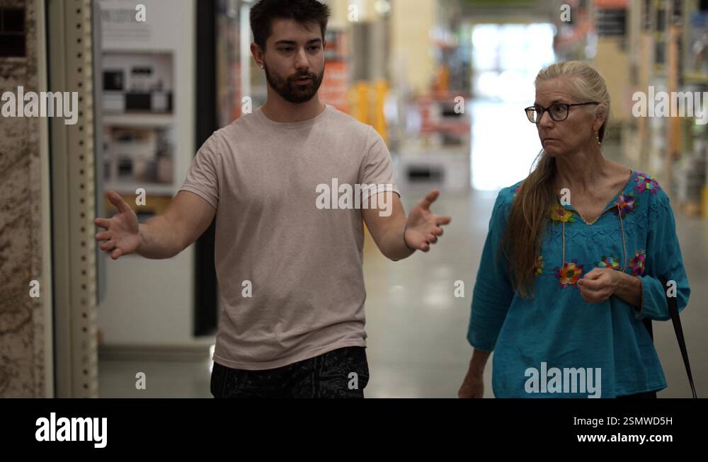 Builder man and client mature woman walk in a large big box hardware ...