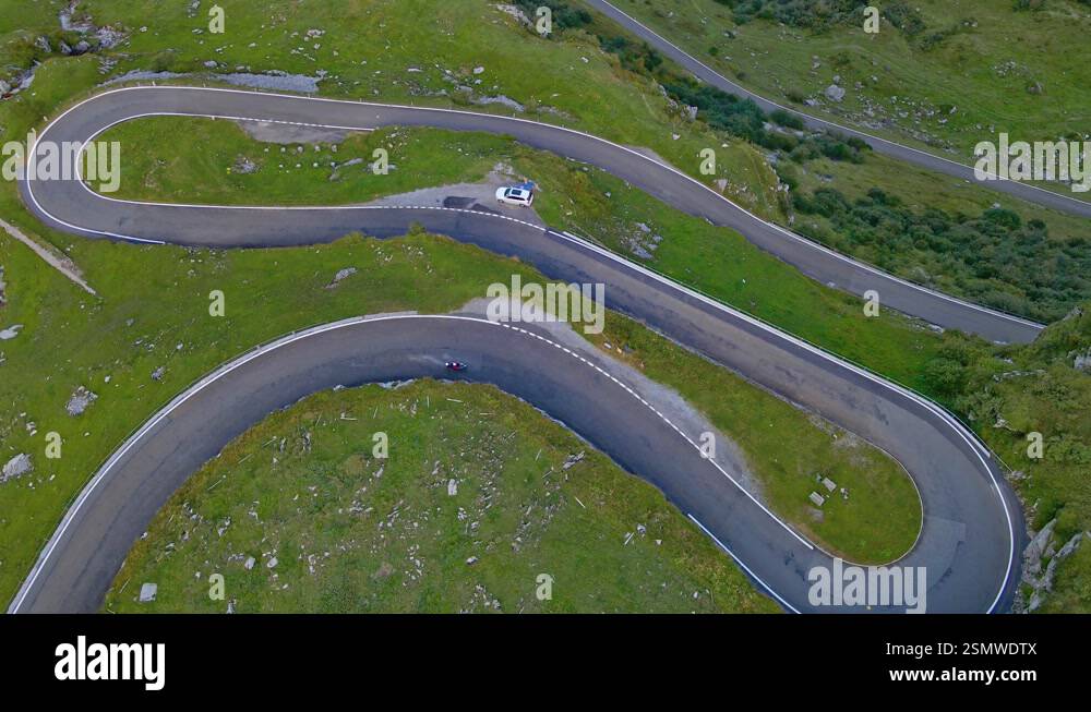 winding mountain road curves in the high alps with few traffic, aerial ...