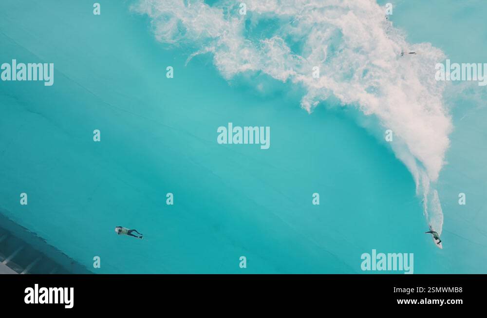 Surfing in the pool. Top down aerial view of the surfers riding wave in ...