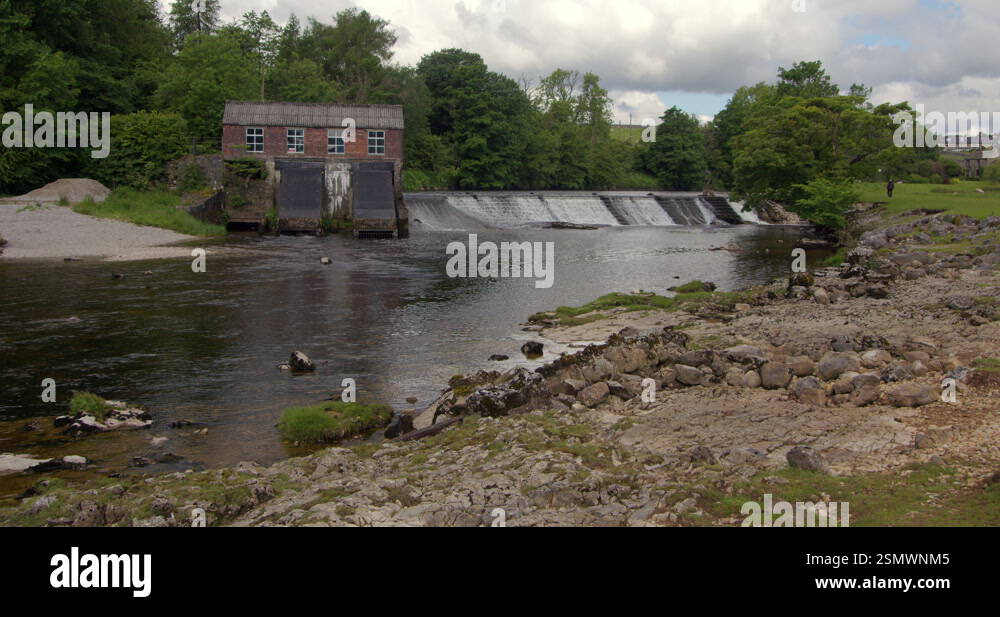 Looking up the river Wharfe with Hydro Power station and man walking in ...