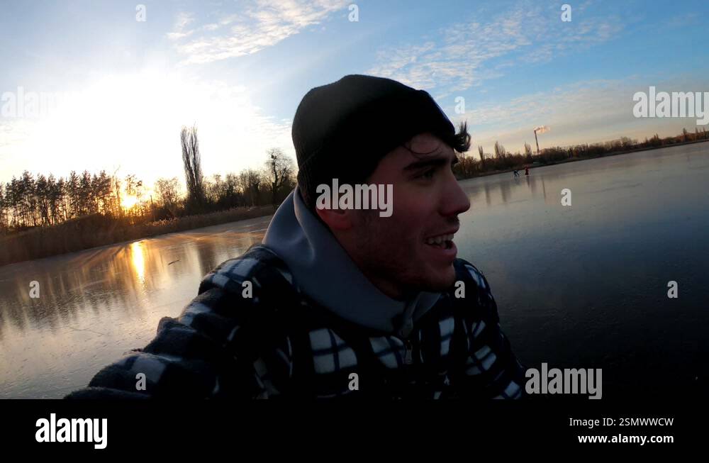Happy male skater sliding on ice rink during beautiful sunset. Young ...