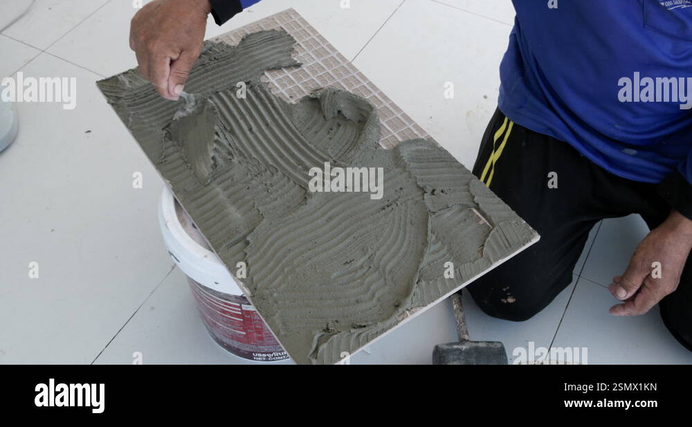 Putting mortar on a panel of ceramic tile using a pallet knife as it is ...