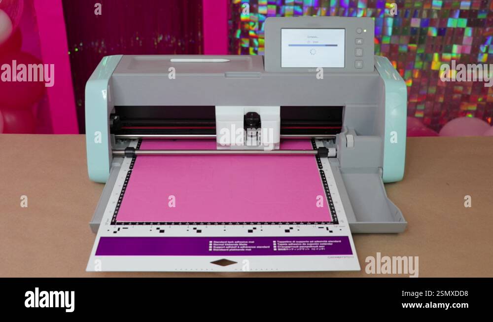 Cutting plotter machine processing pink cardboard in a colorful craft ...