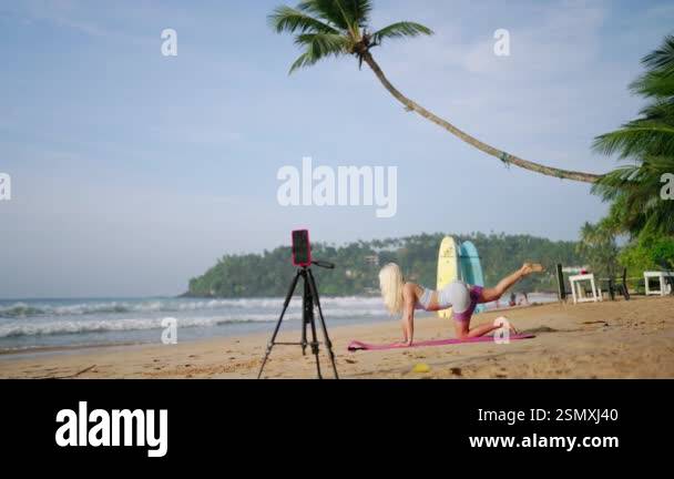 Woman demonstrates pose on mat, smartphone and tripod capture online ...