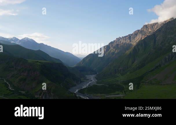 Aerial view of the Caucasus mountains with river valley and green hills ...