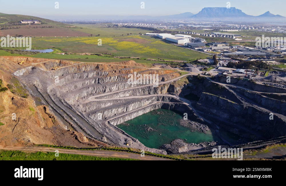 Massive open-cast mine quarry in lush fertile landscape. Aerial dolly ...