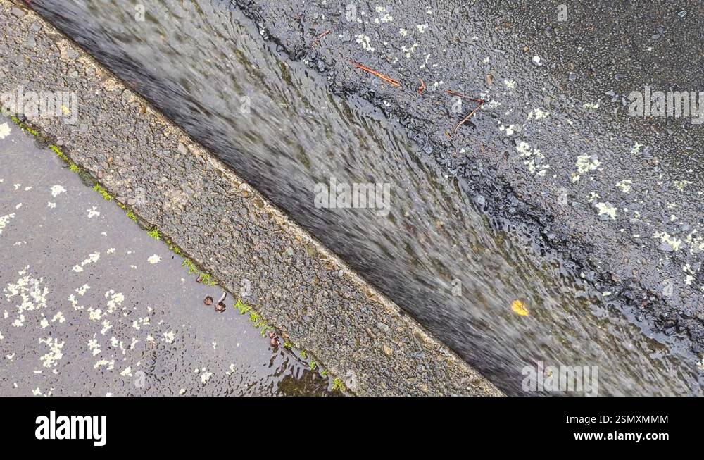 Top down of fast flowing water in road side drain during heavy raining ...